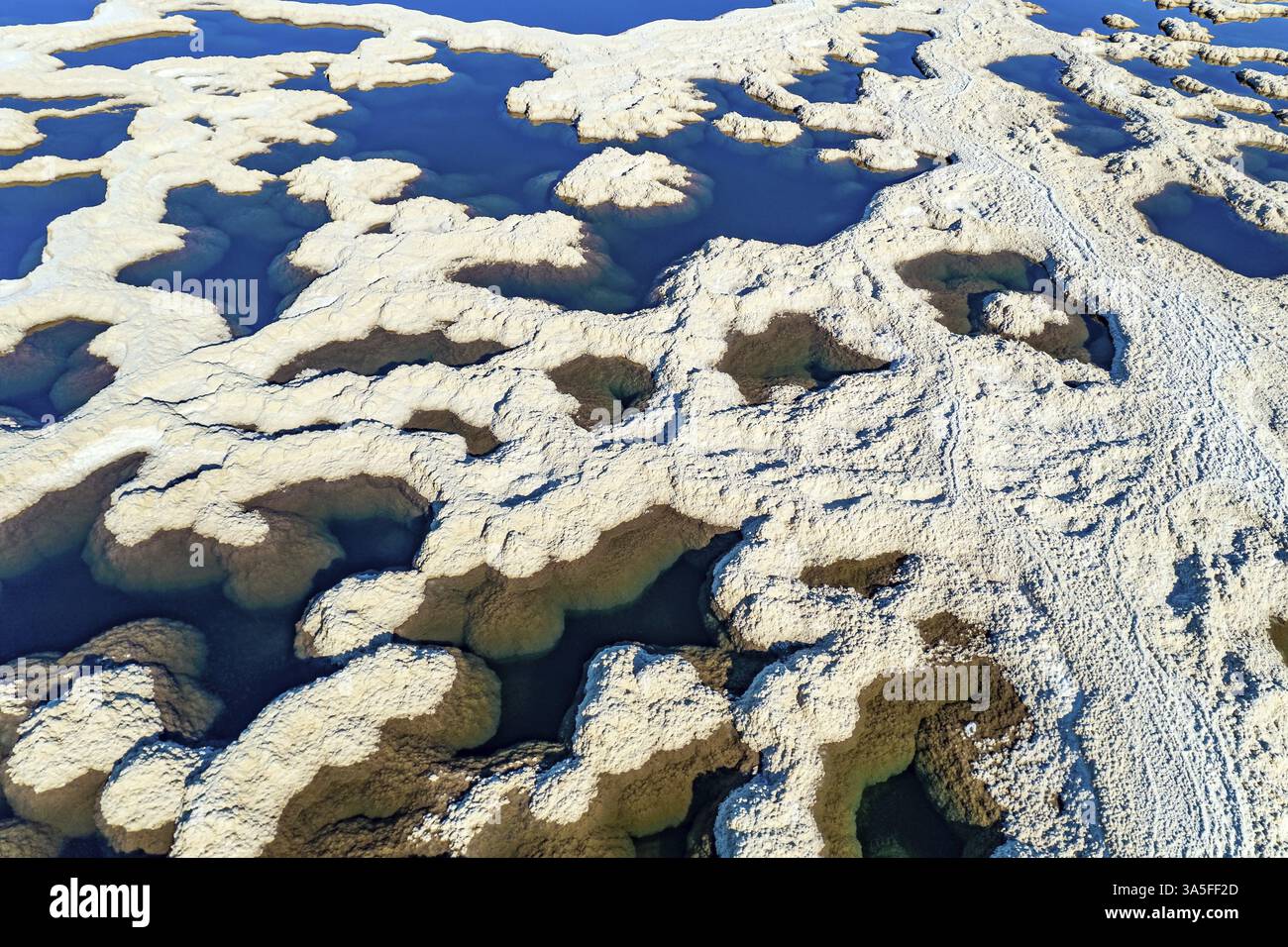 Evaporated salt forms bizarre patterns on the blue water. Sunny winter ...