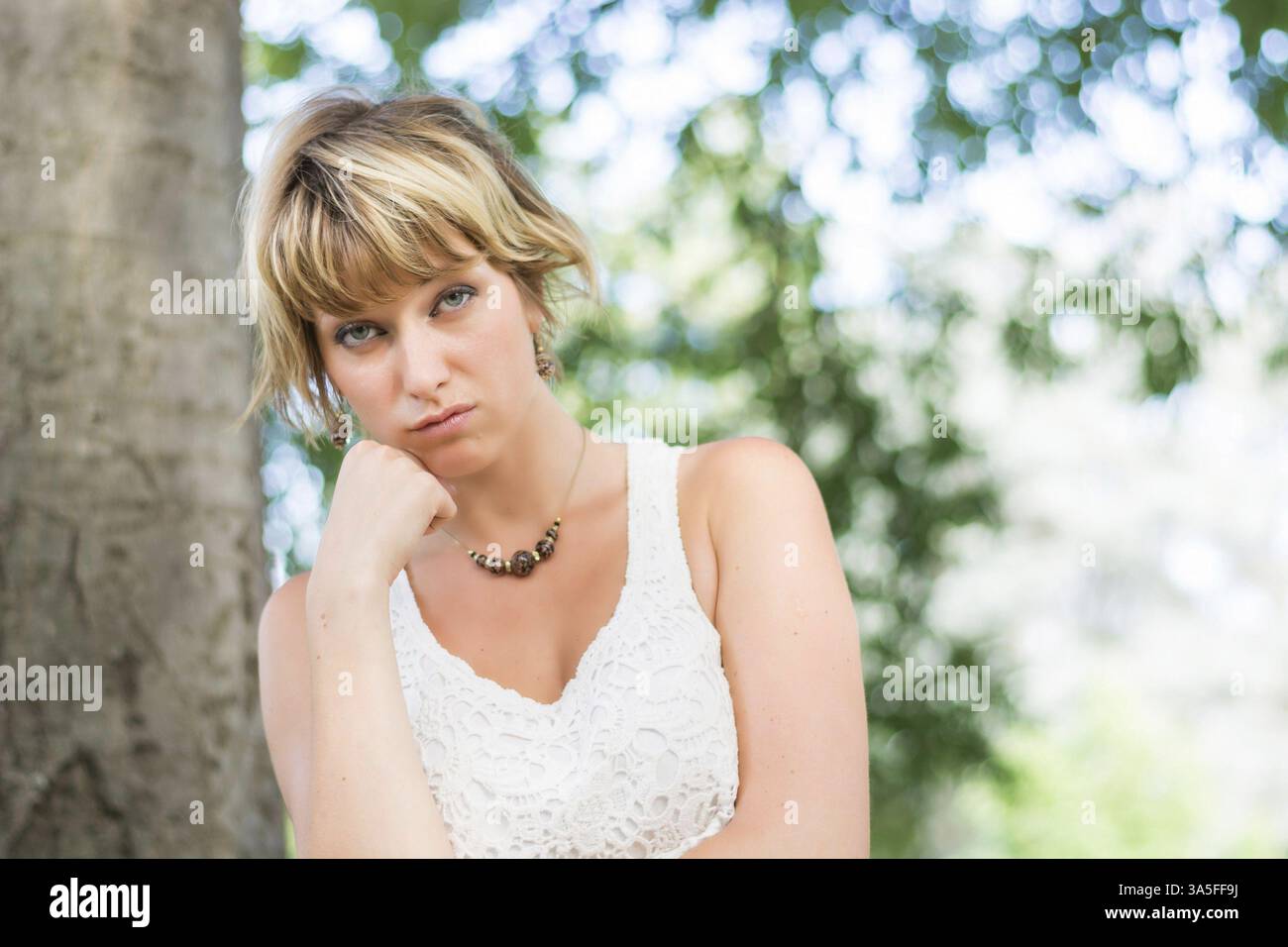 Attractive young blonde woman bored, standing outdoor in nature ...
