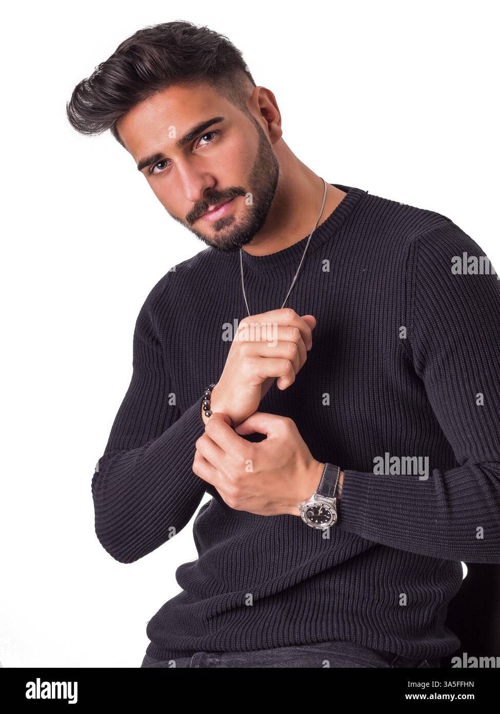 Attractive young man sitting on stool, wearing wool sweater, isolated ...