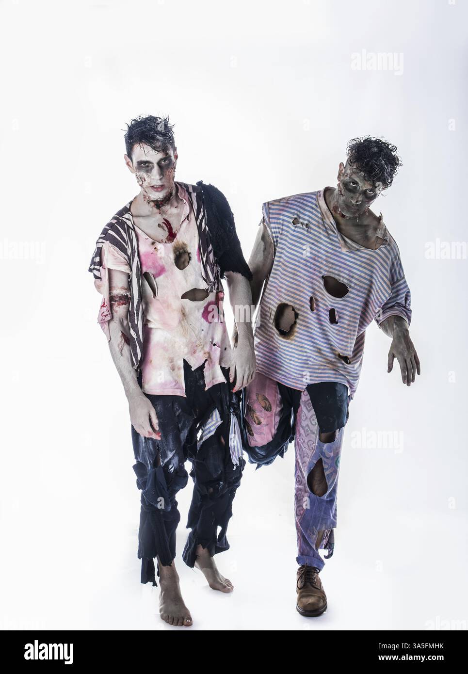 Two male zombies standing on black background walking towards camera ...