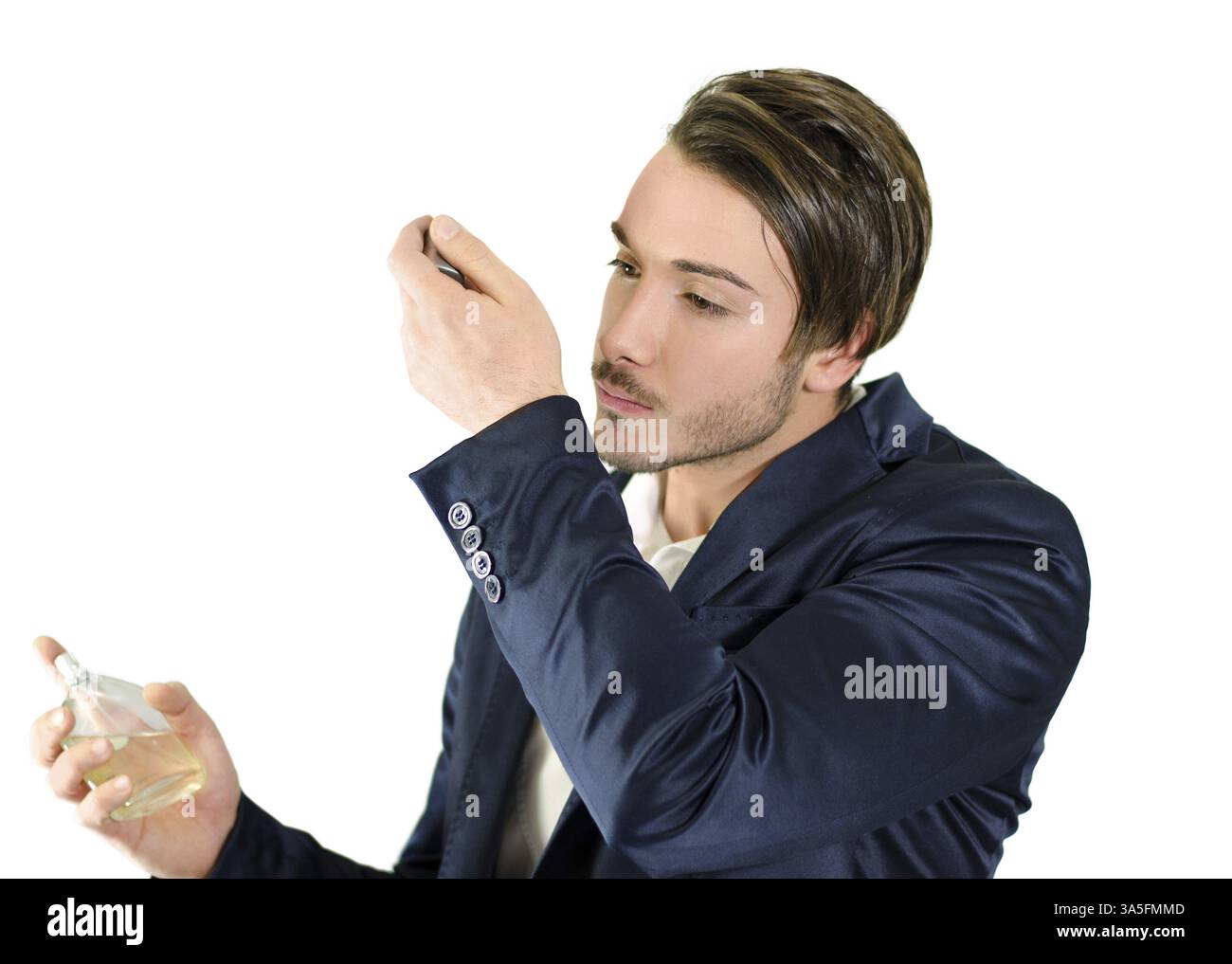 Attractive young man spraying and smelling fragrance or cologne ...