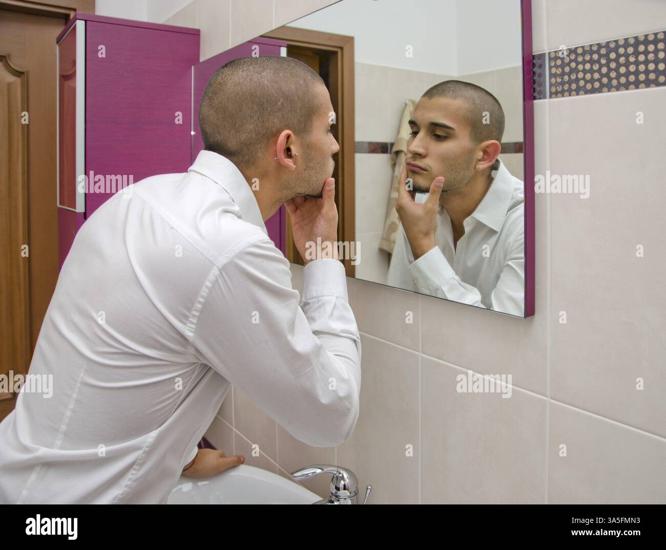 Young man looks mirror watching hi-res stock photography and images - Alamy