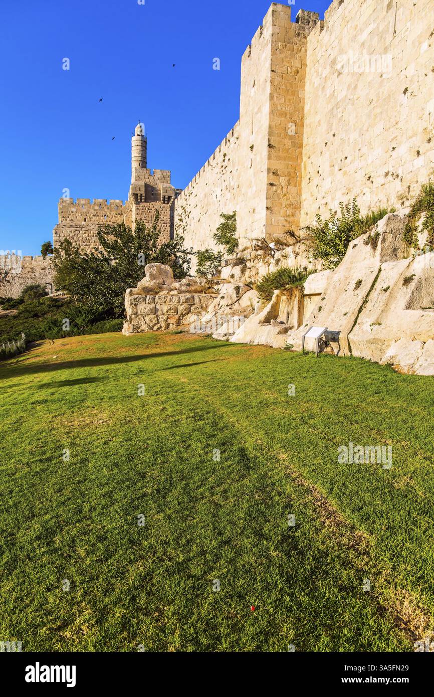 The fortress wall of old Jerusalem. Adorable green lawn growing under ...