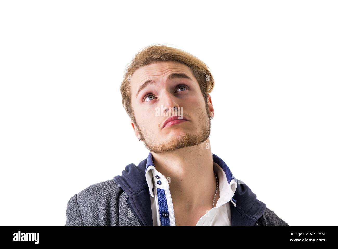 Attractive young man thinking, looking up with hand on his chin ...