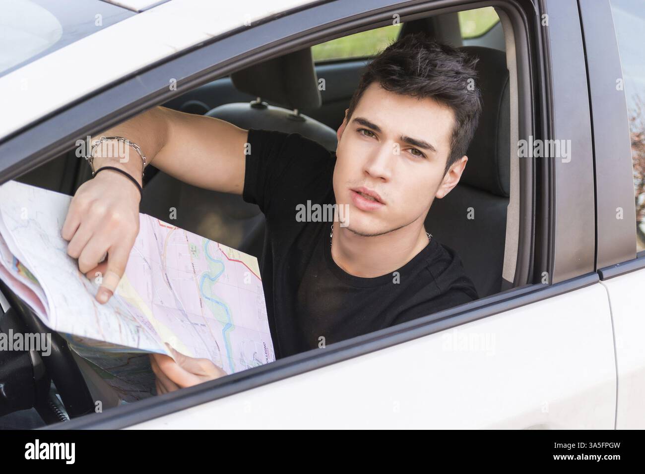 Handsome Young Man showing map inside of a car, asking for directions ...
