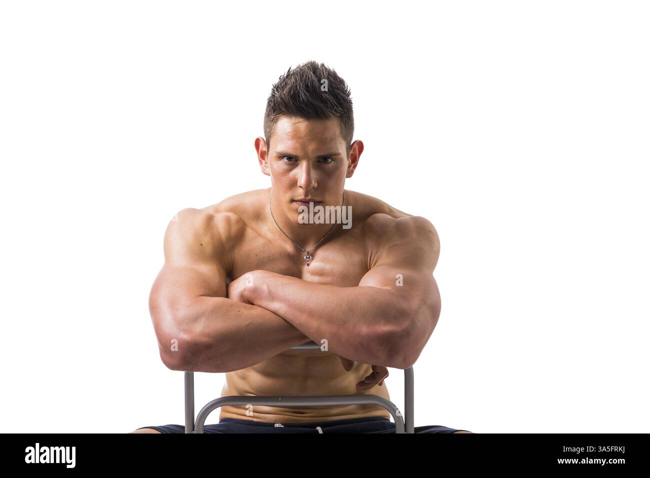 Muscular young bodybuilder sitting on chair, looking at camera ...