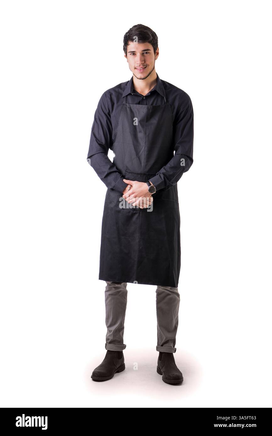 Young chef or waiter posing, wearing black apron and shirt isolated on ...