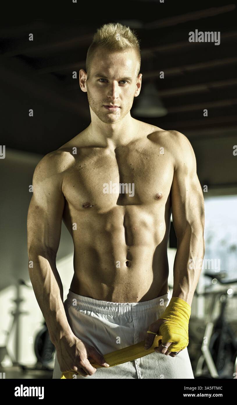 Muscular young man wrapping bandage around his hands for boxing Stock ...