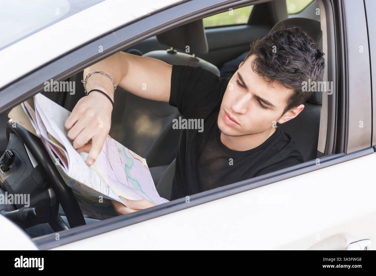 Handsome Young Man showing map inside of a car, asking for directions ...