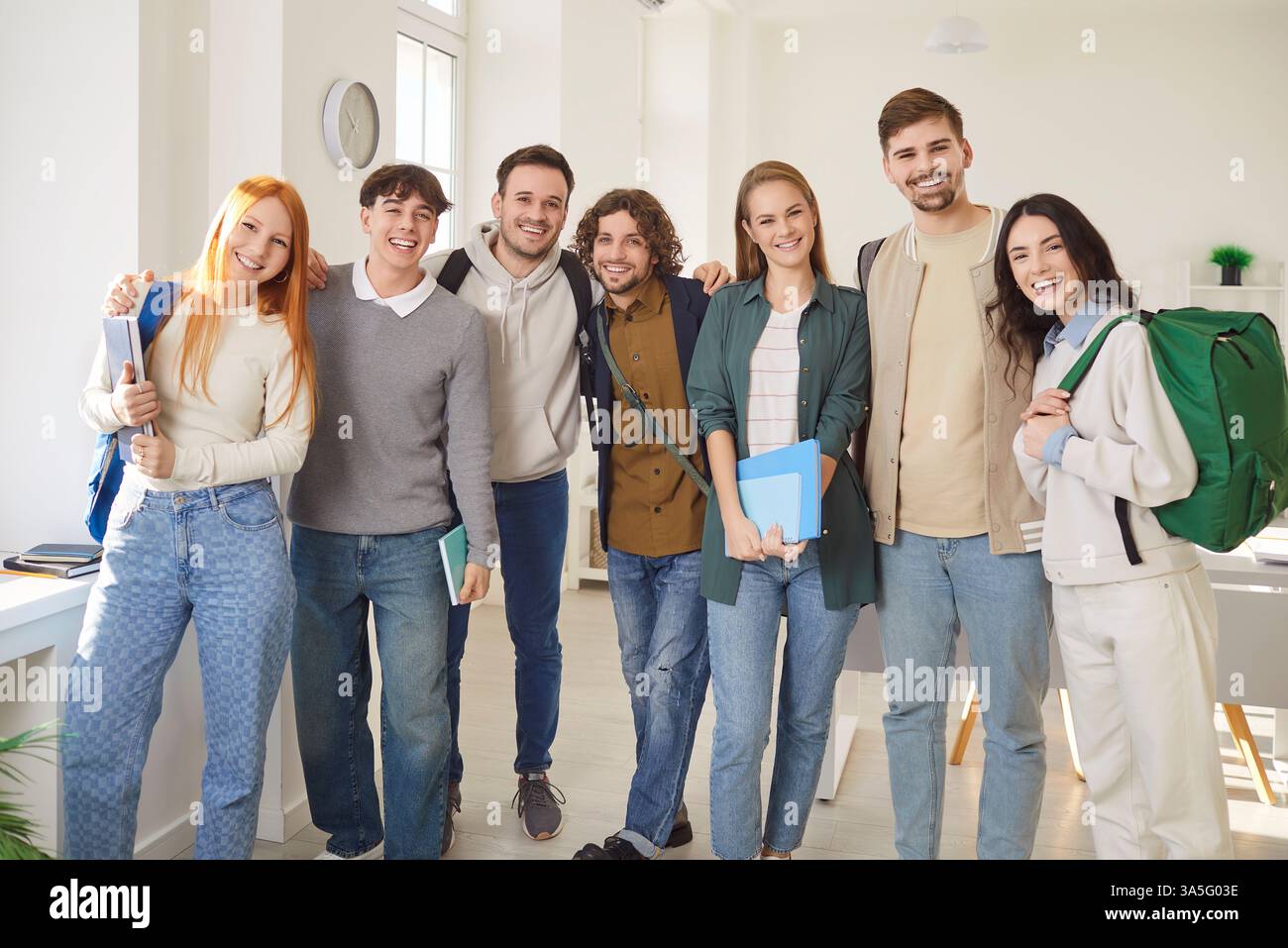 Happy young students hugging in classroom, smiling at camera and ...