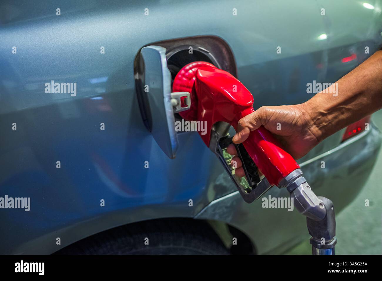 Hand refilling the car with fuel at the refuel station. Man pumping gas ...