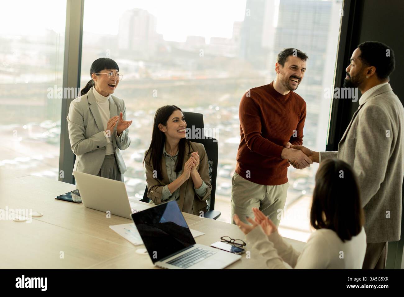 Colleagues gather in a bright, contemporary office to celebrate a ...