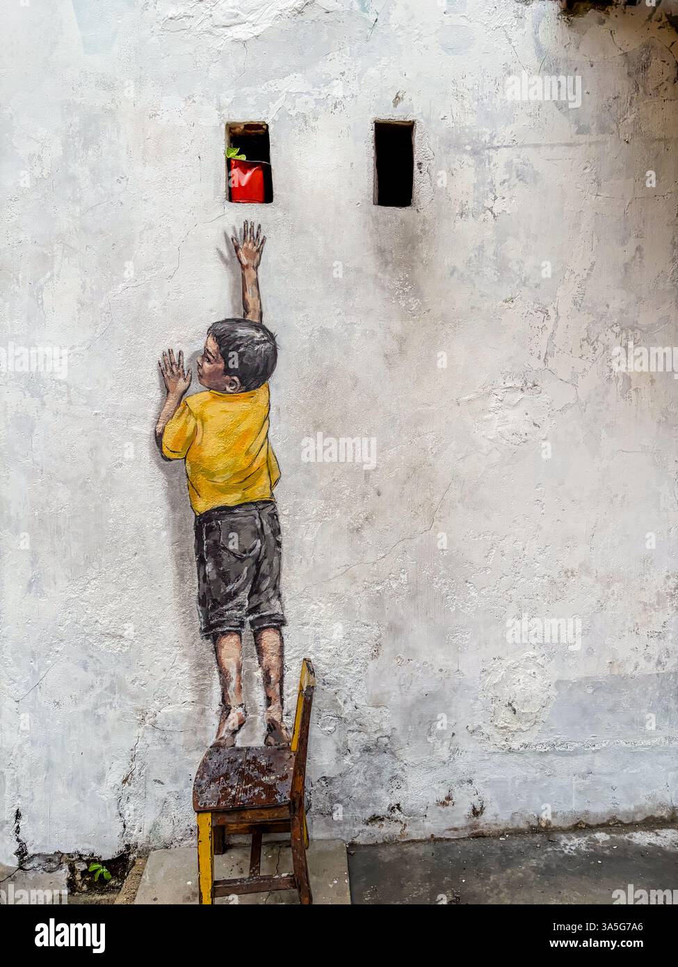 Close-up of street art showing a boy reaching up the side of a wall ...