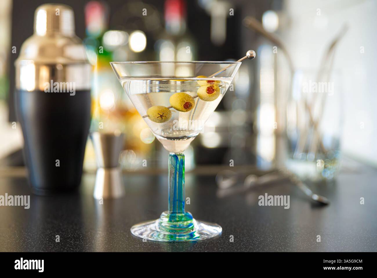 A Glass of classic dry martini cocktail with green olives on a bar ...
