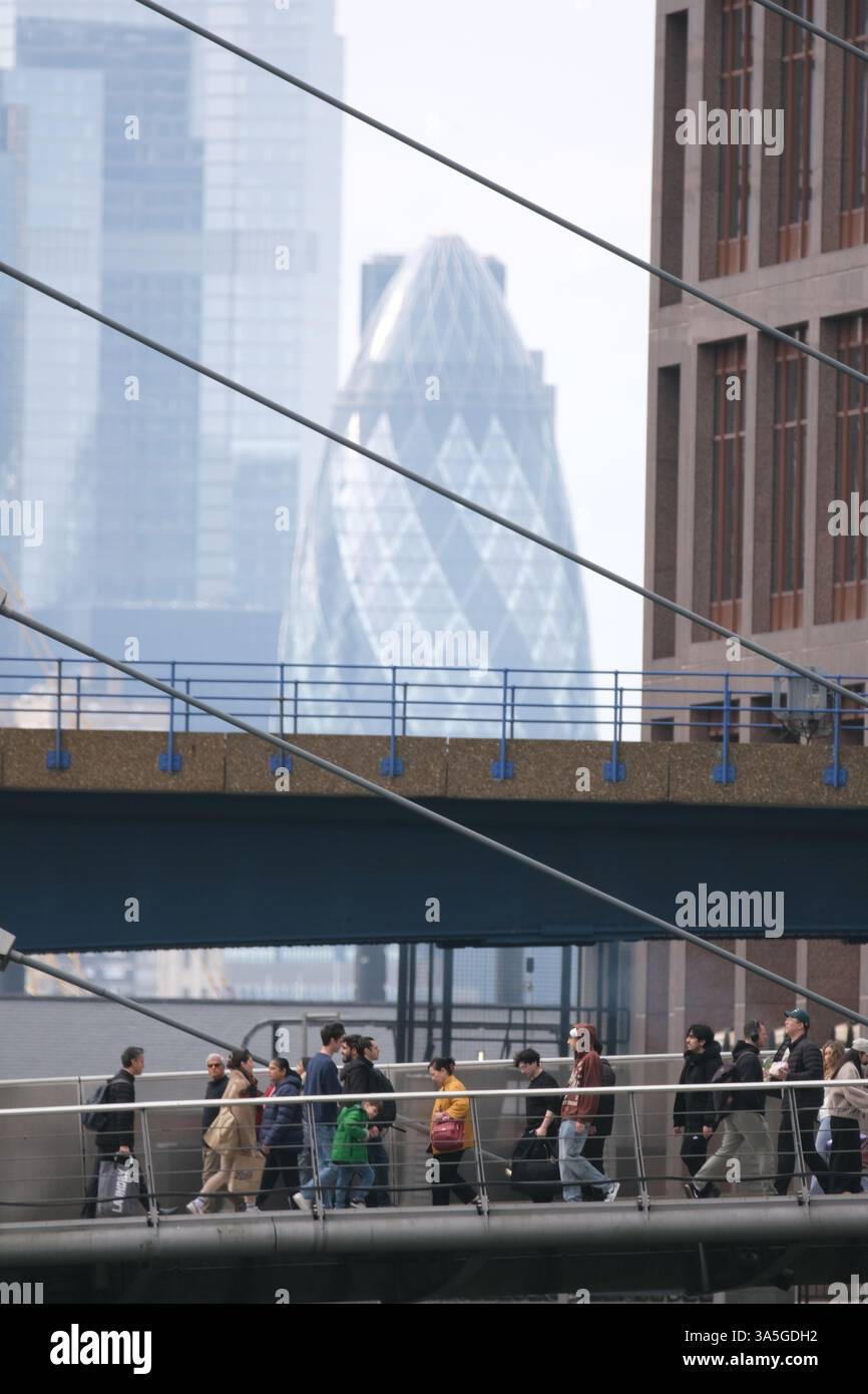Pedestrians crossing South Dock footbridge with The Gherkin as backdrop ...