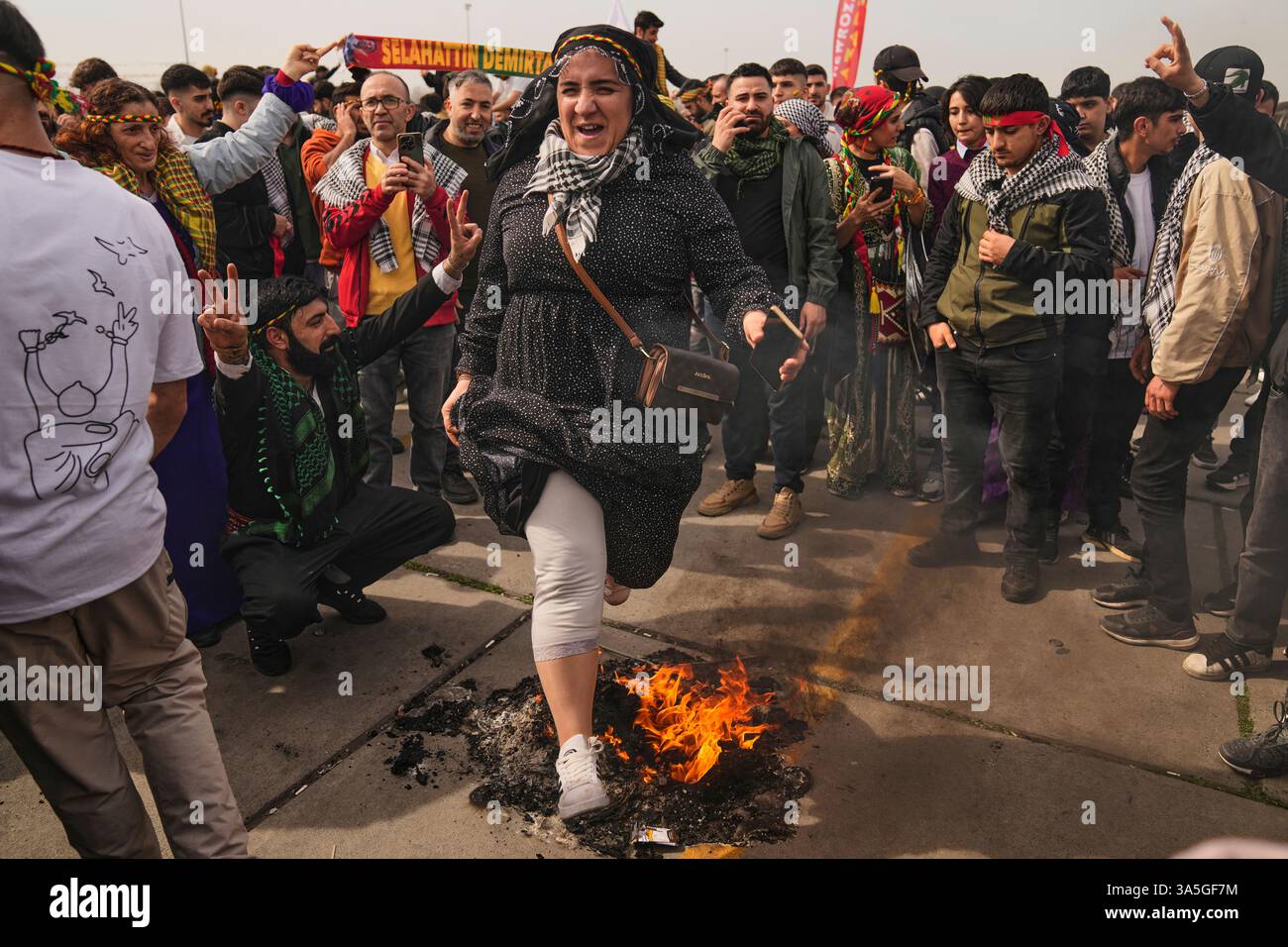 A woman jumps over a bonfire during a gathering to celebrate Nowruz ...