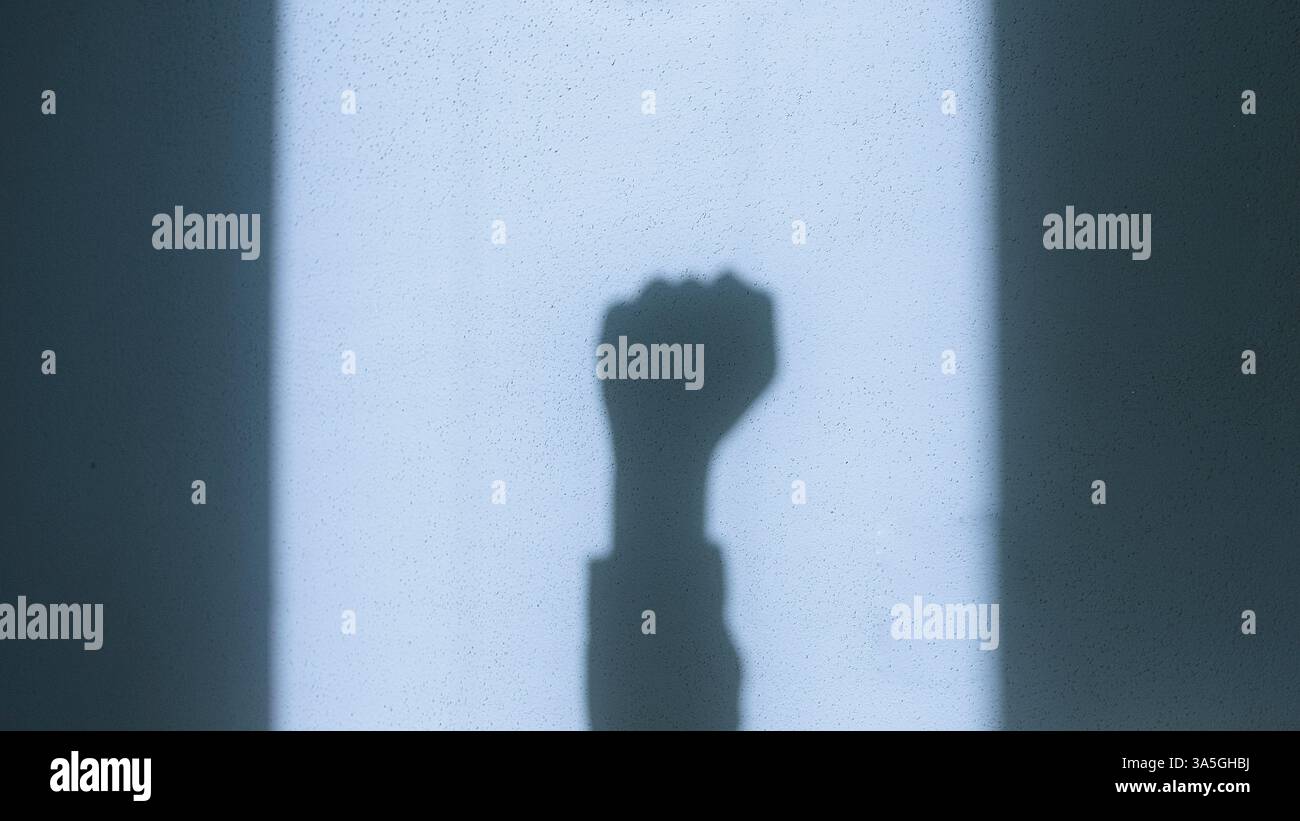 Shadow of a Raised Fist Cast by Sunlight on a Wall Stock Photo - Alamy
