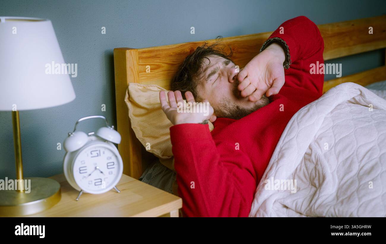 Sleepy Man Waking Up and Yawning in Bed with Alarm Clock Ringing Stock ...