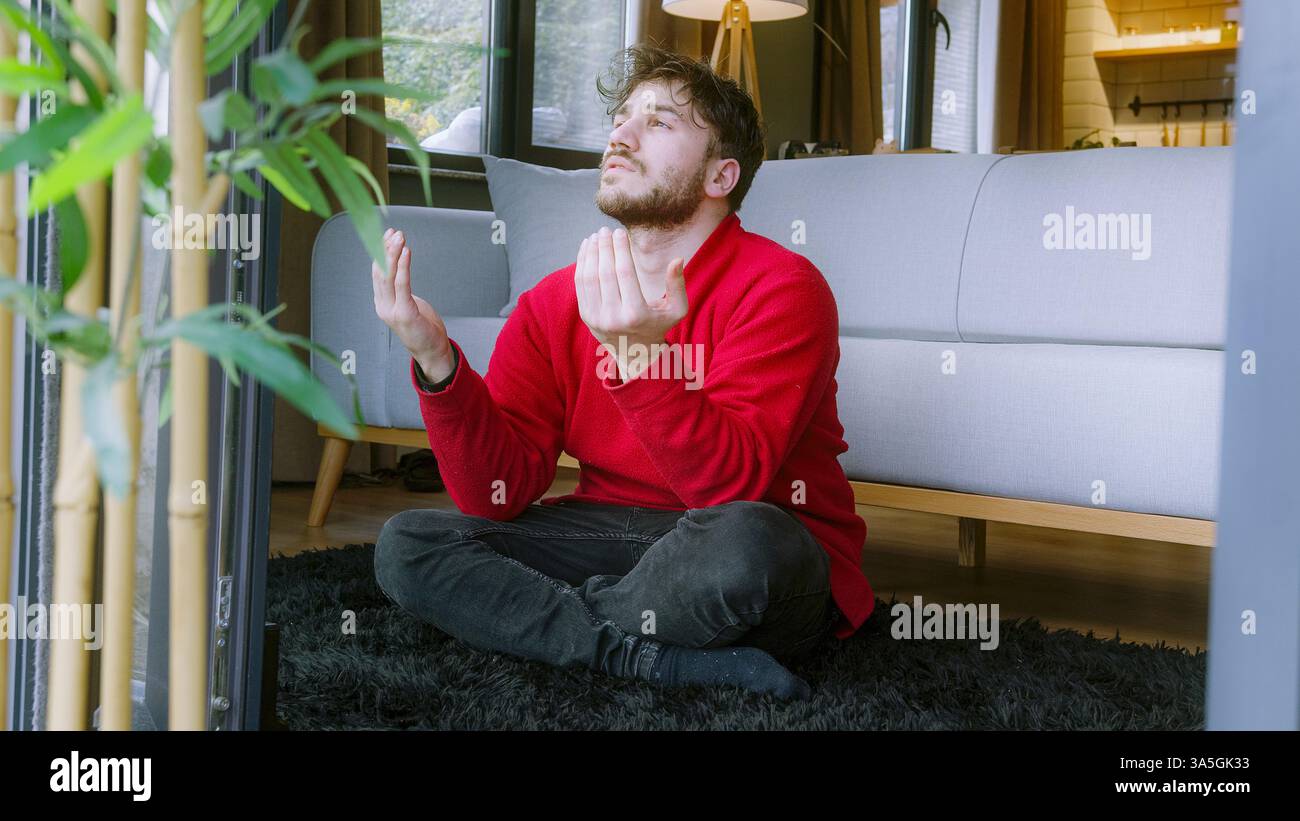 Young Man Praying at Home, Sitting Cross-Legged on the Floor with Hands ...