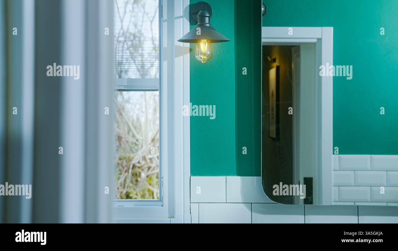 Vintage-style wall lamp illuminating a modern bathroom with green walls and white tiles, cozy ...
