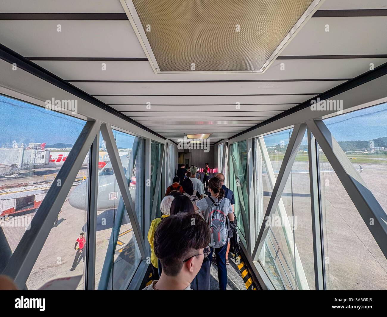 Passengers walking along airport jetway, boarding to an AirAsia ...