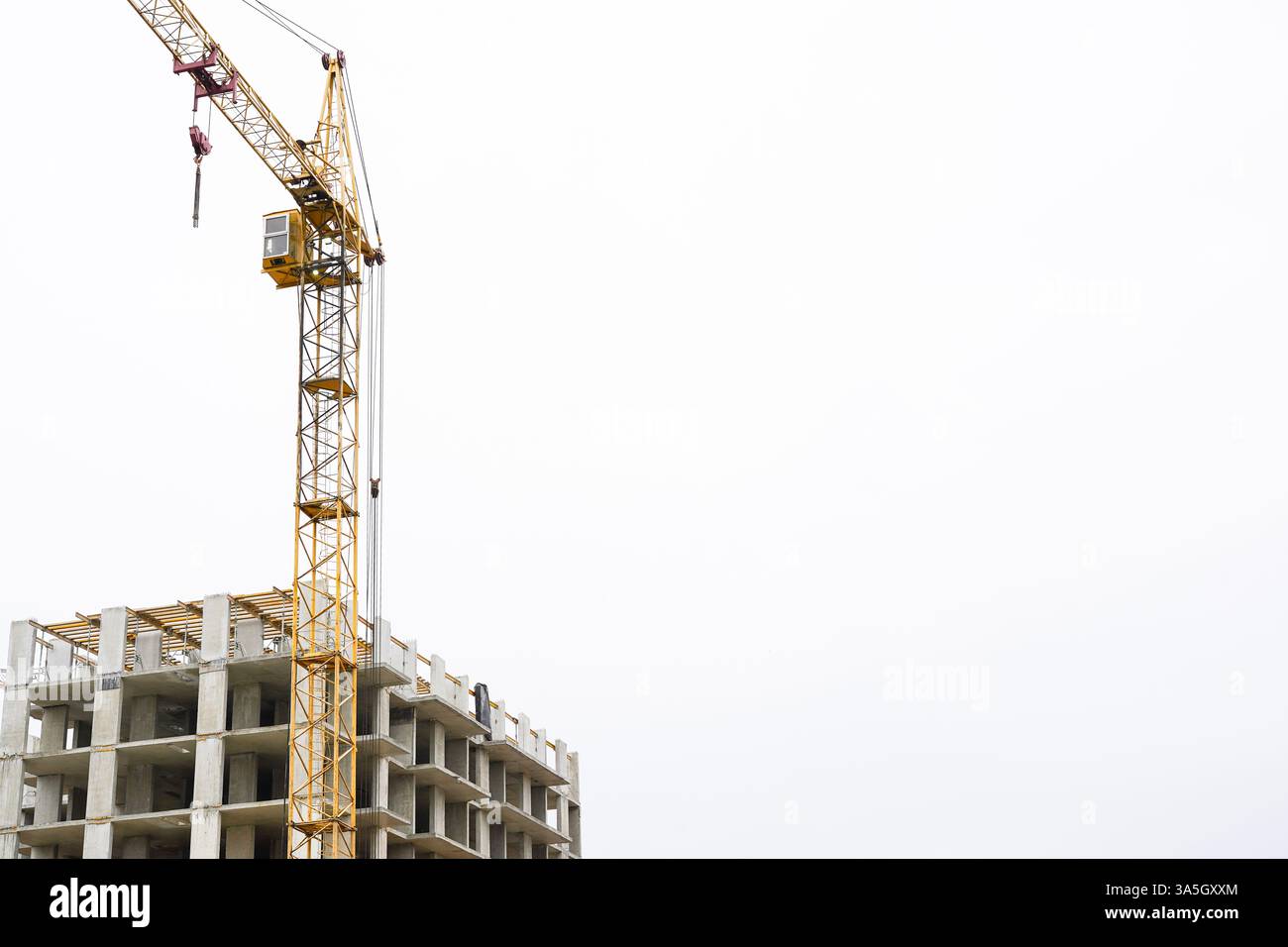 a tall yellow construction crane towering over a multi-story concrete ...