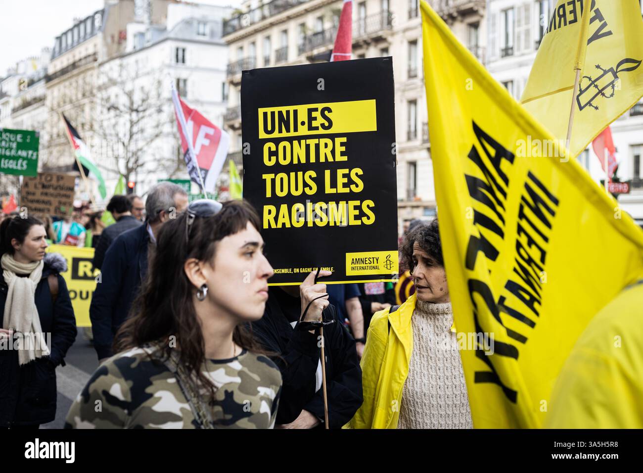 A protestor holds a placard that says "United against all forms of ...