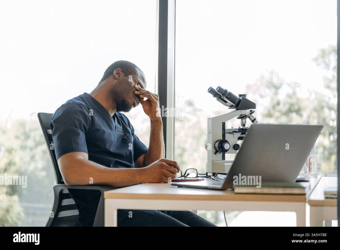 Tired, sitting and taking a break. Scientist is working indoors ...