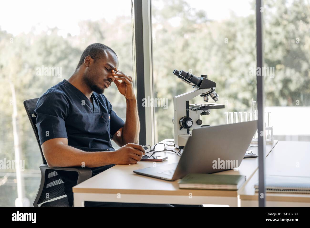 Tired, sitting and taking a break. Scientist is working indoors ...