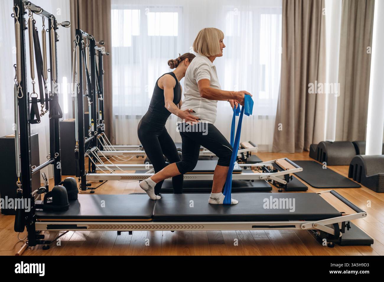 Blue colored resistance loops in hands for the legs. Female trainer is ...