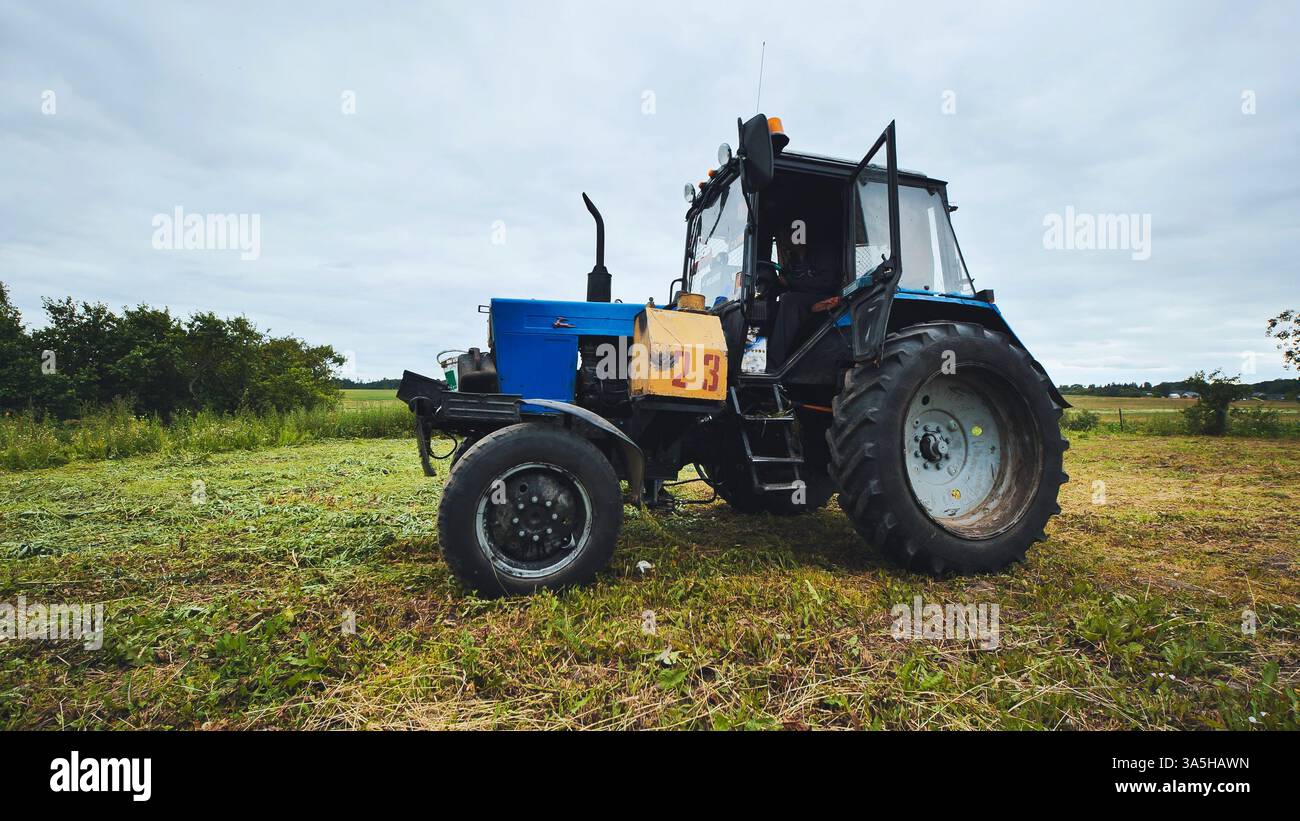 Blue tractor staying parked in a mowed field under cloudy sky Stock ...