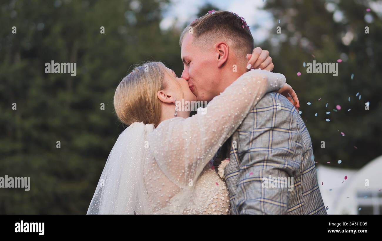 Newlyweds sharing passionate kiss amid falling confetti, marking ...