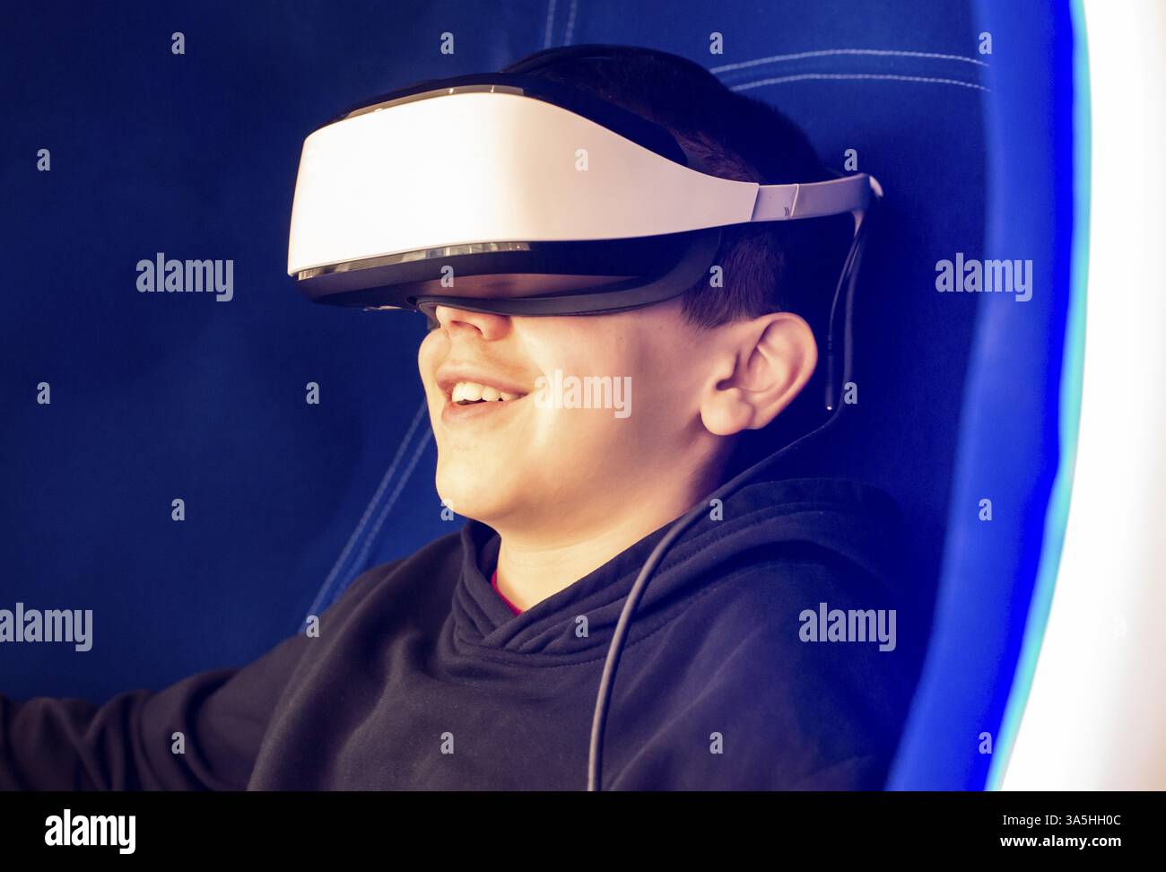 Child playing game with VR glasses. Blue illuminated cabin with ...