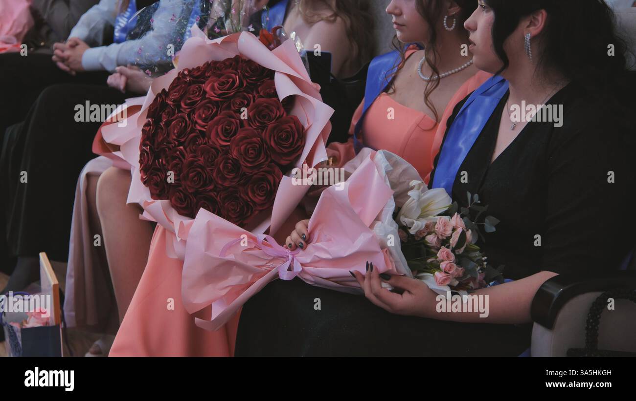 Young graduates celebrating academic success, clutching colorful flower ...