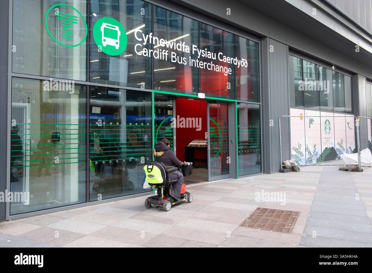 Disabled person sitting riding mobility scooter outside Cardiff Bus ...