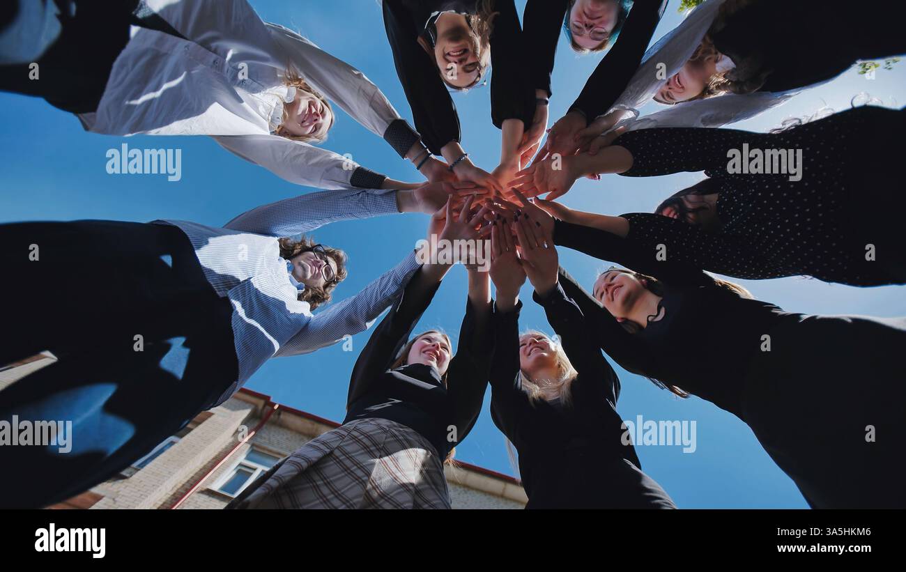 Happy students come together, joining hands in a circle to celebrate ...