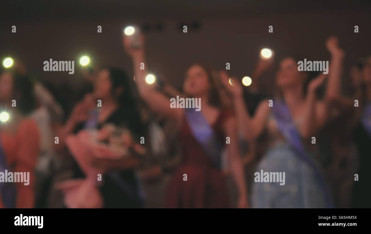 Group of students waving illuminated cell phones at graduation party ...