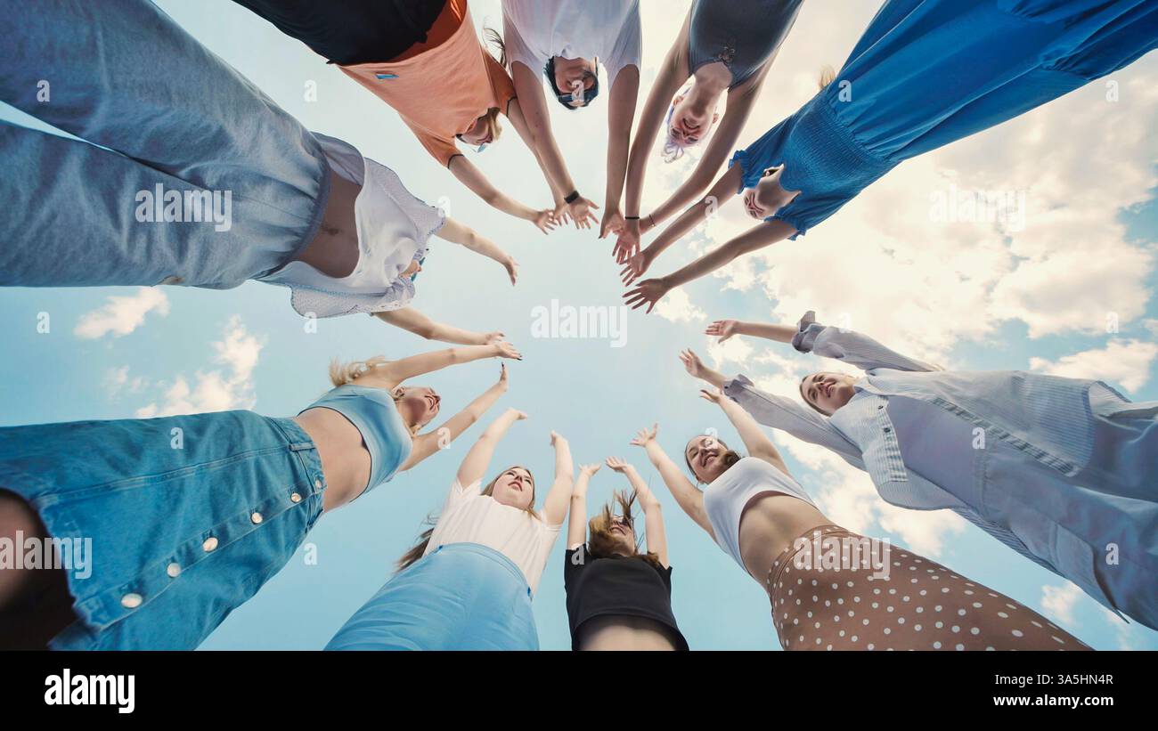 School friends joining hands in a circle, raising arms in celebration ...