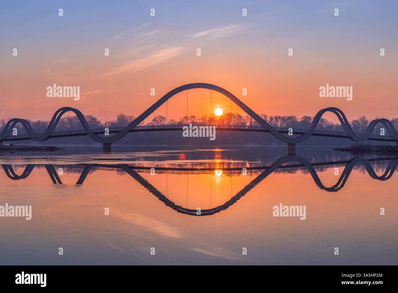 The rising sun crowns the wavy pedestrian bridge in Kyiv, casting ...