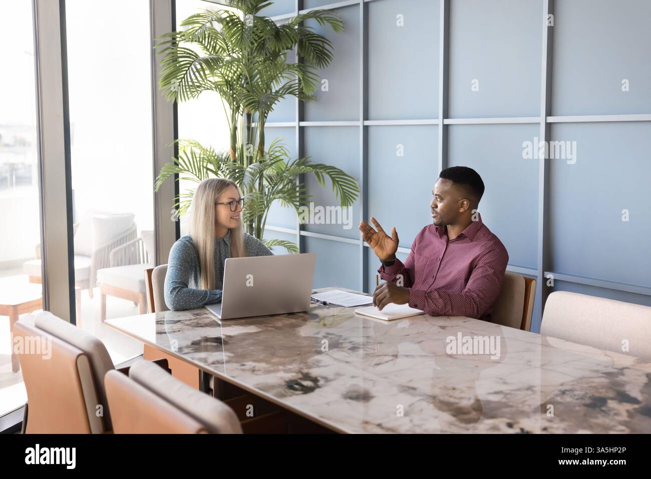 Two multinational teammates talking during meeting in boardroom ...