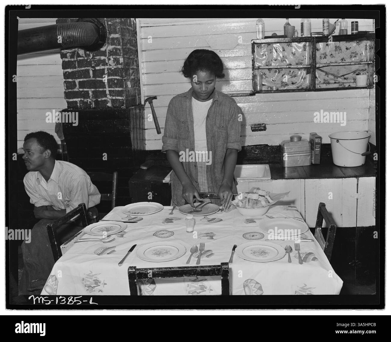 Mrs. James Robert Howard sets the table for supper in their home in ...