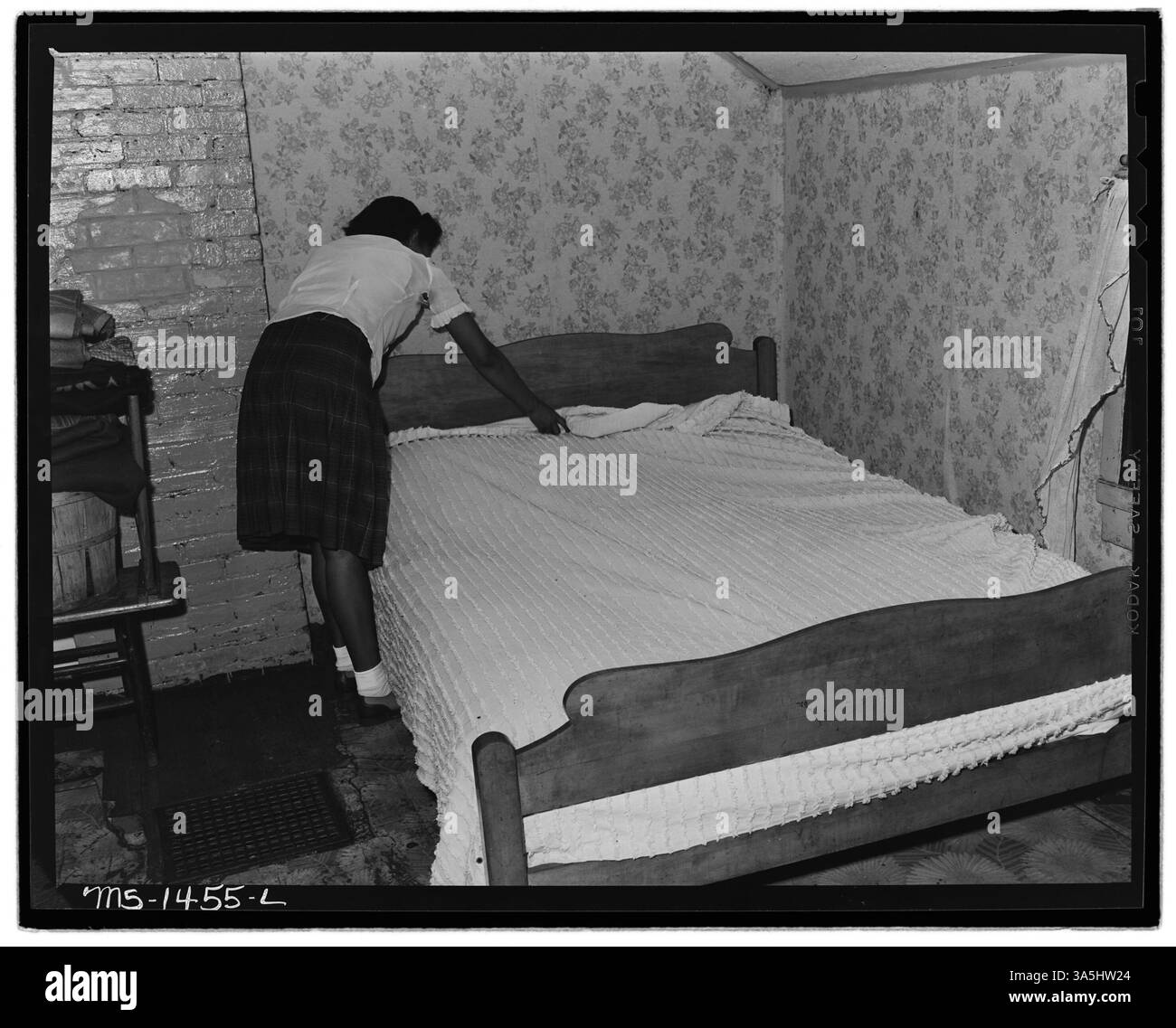 Mrs. James Robert Howard arranges the bed in their three-room house ...