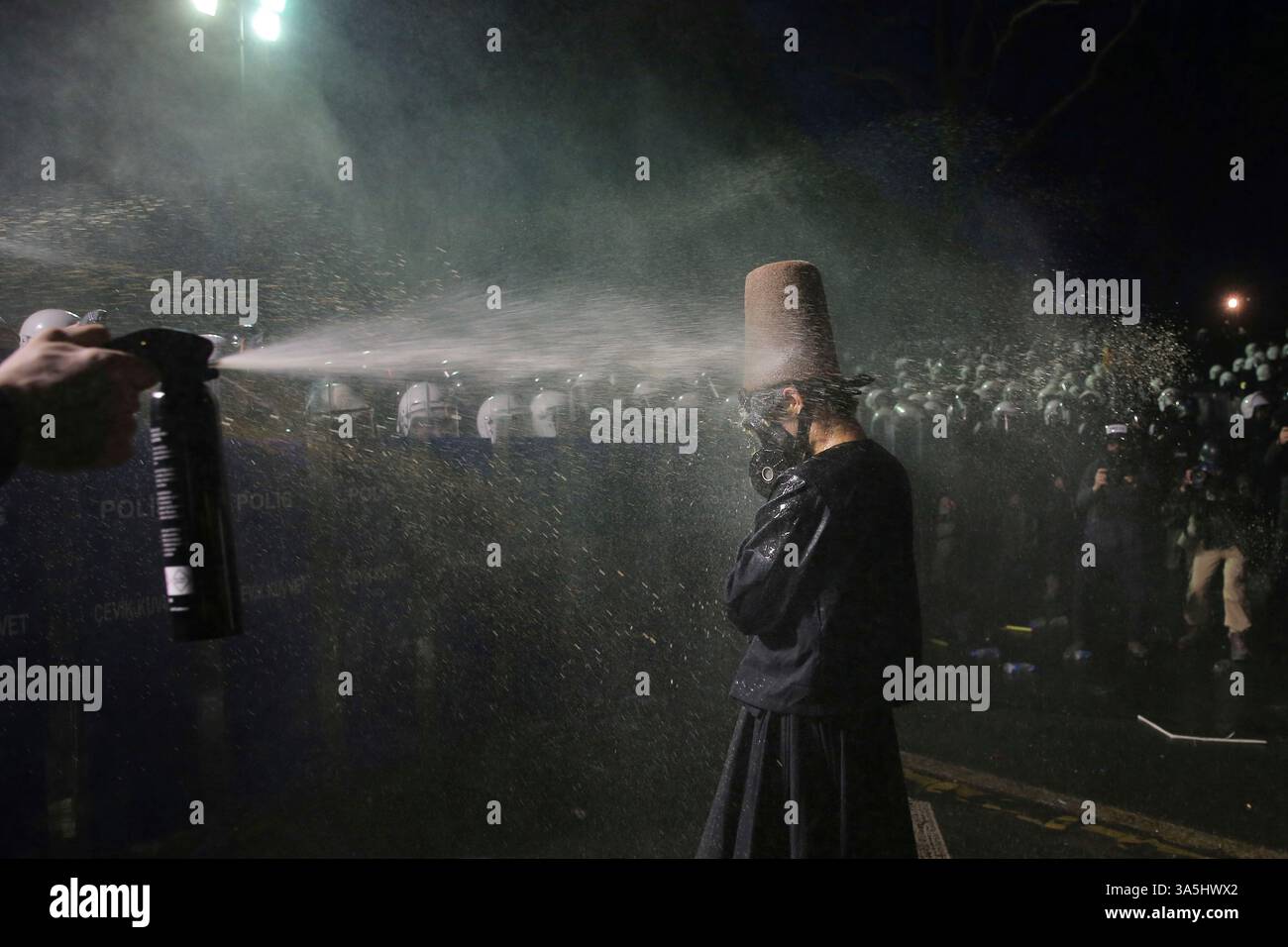 Riot police officers use pepper spray to clear a protester during a ...