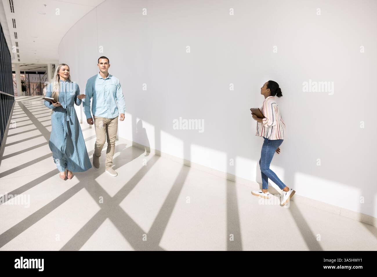Three colleagues walking office hall hi-res stock photography and ...