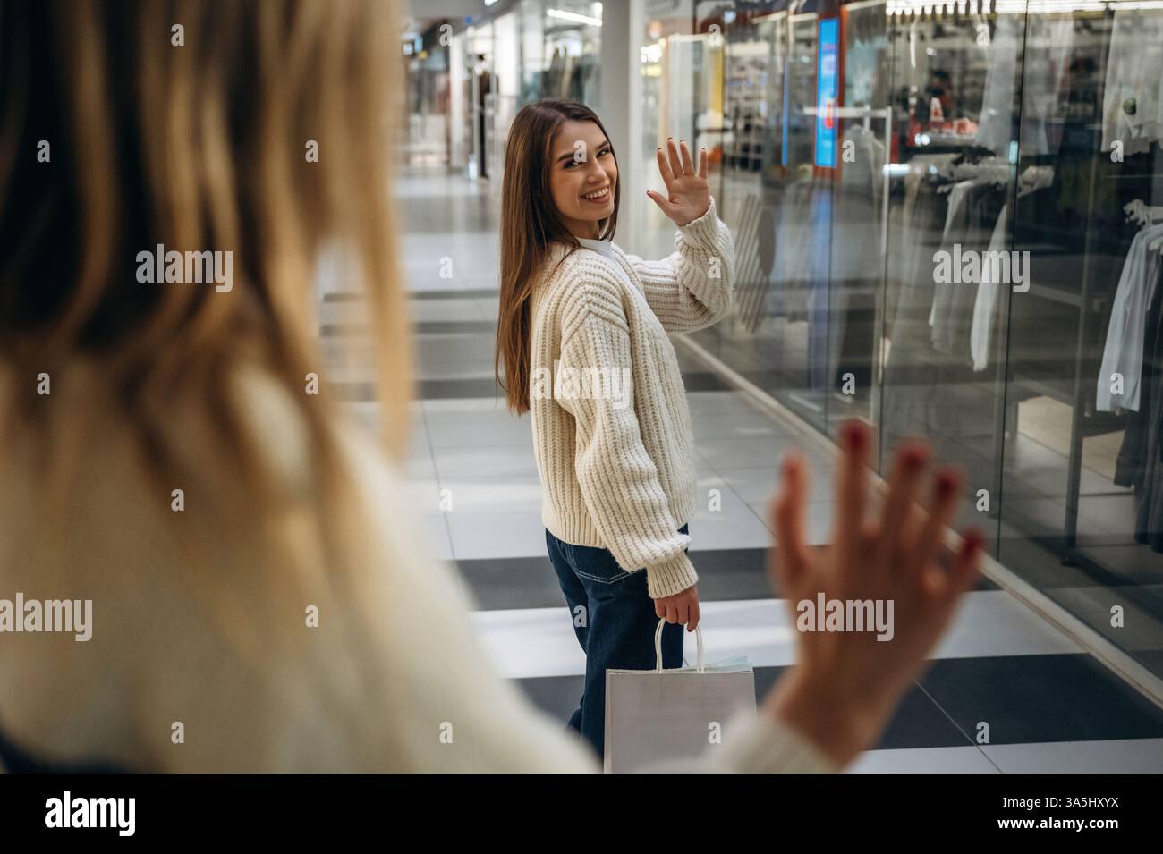 Two woman are in the mall, showing goodbye hands gesture Stock Photo ...