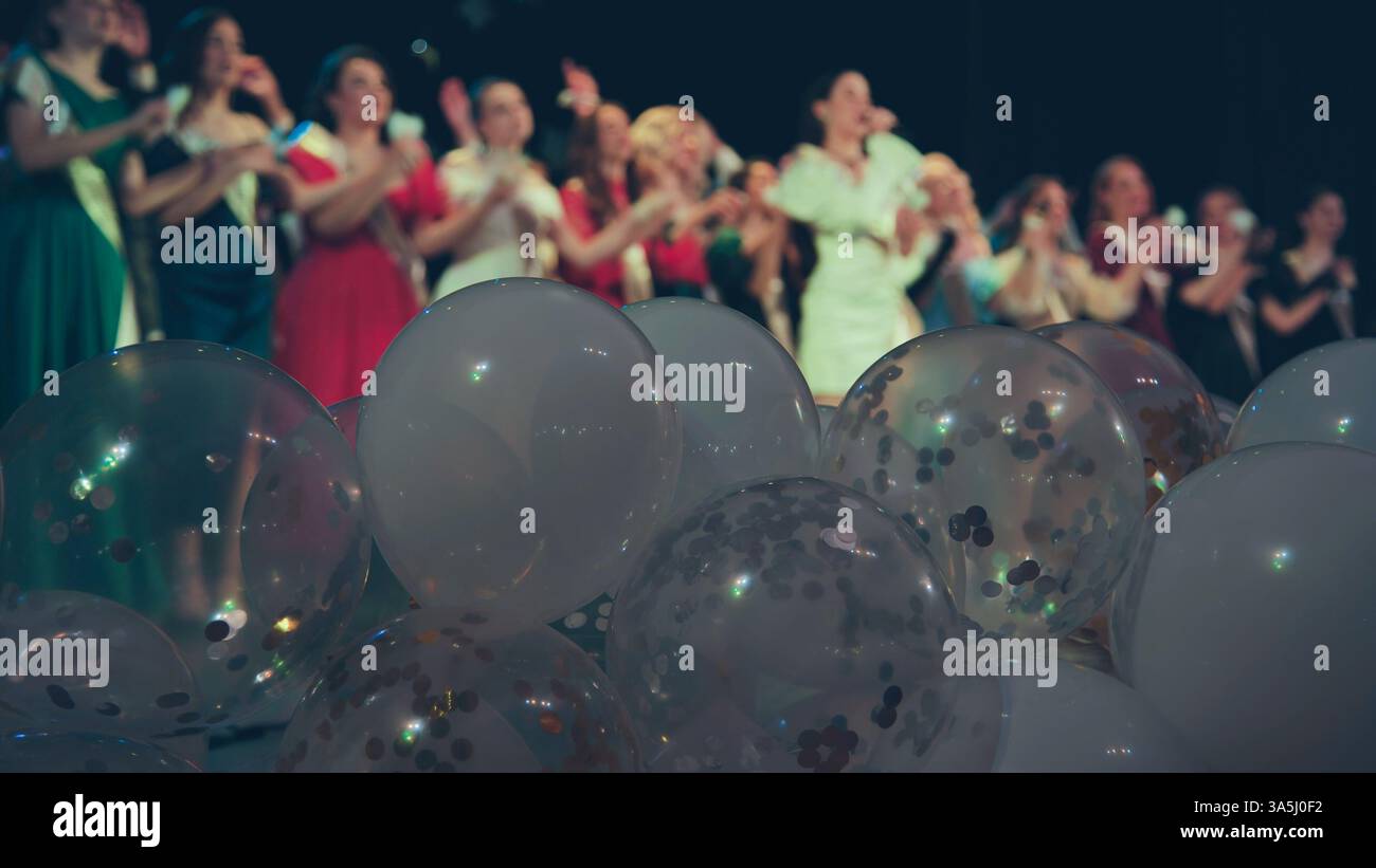 School friends clapping and celebrating on a stage, with balloons in ...