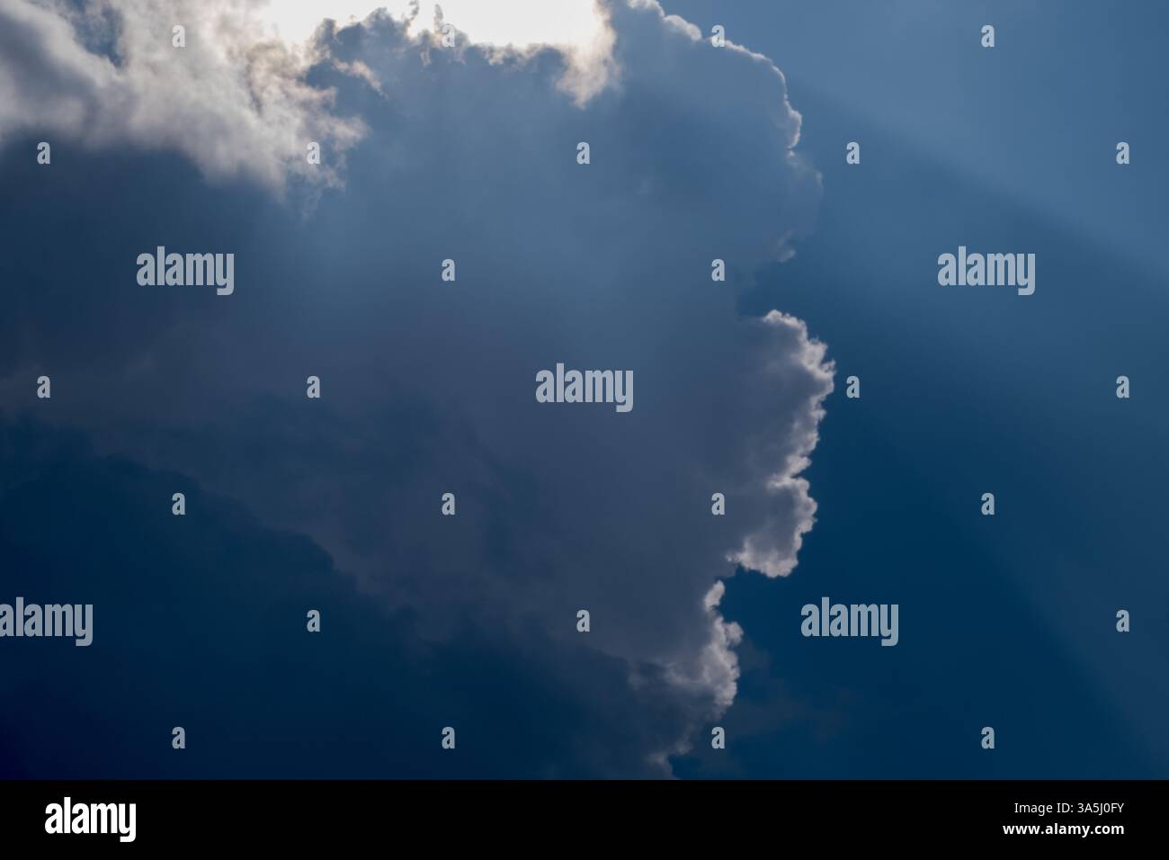 Sun piercing through fluffy clouds of a blue sky Stock Photo - Alamy