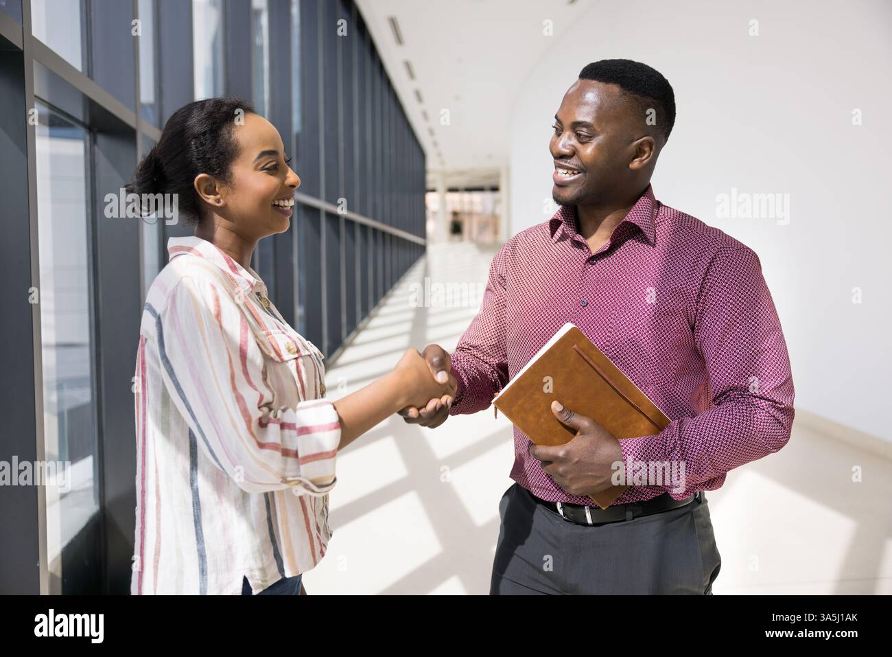 Friendly African colleagues greeting each other with handshake stand in ...