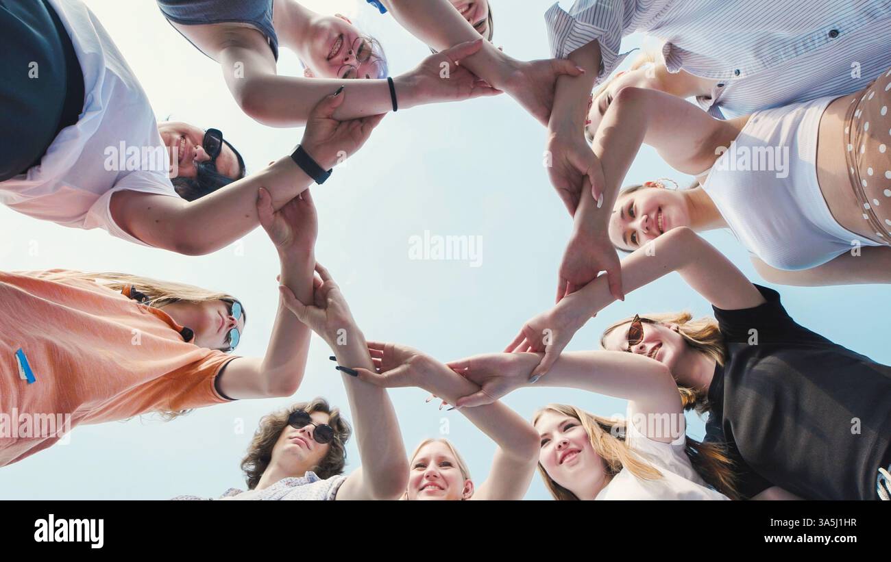 Group of students joining hands forming a circle outdoors, symbolizing ...