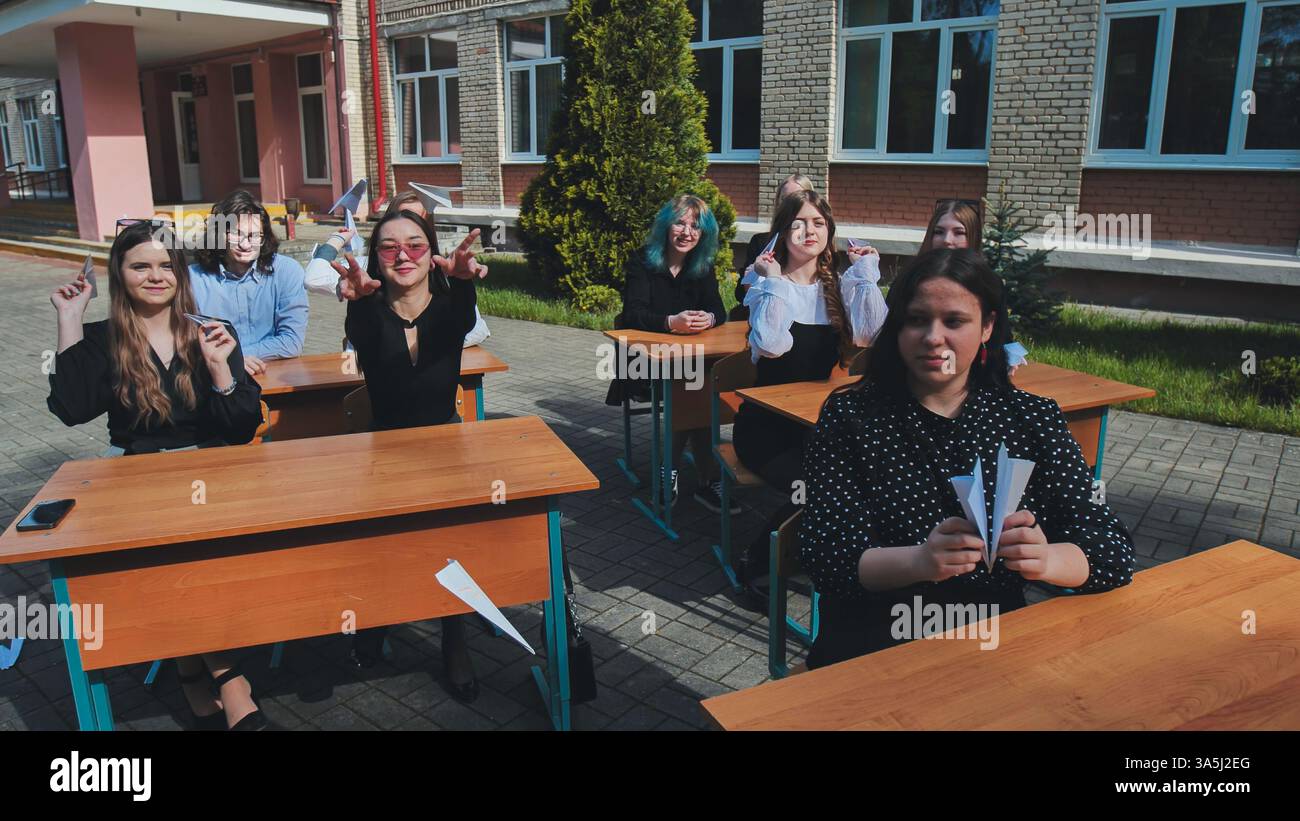 Happy students having fun during recess in the schoolyard, flying paper ...